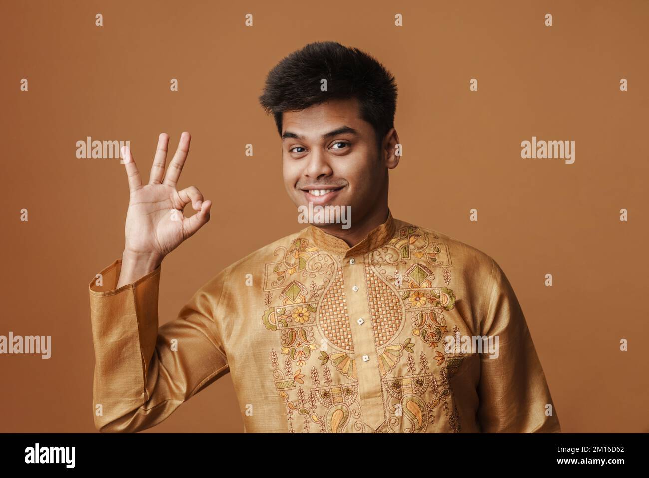 Young indian man smiling and gesturing okay sign isolated over yellow ...