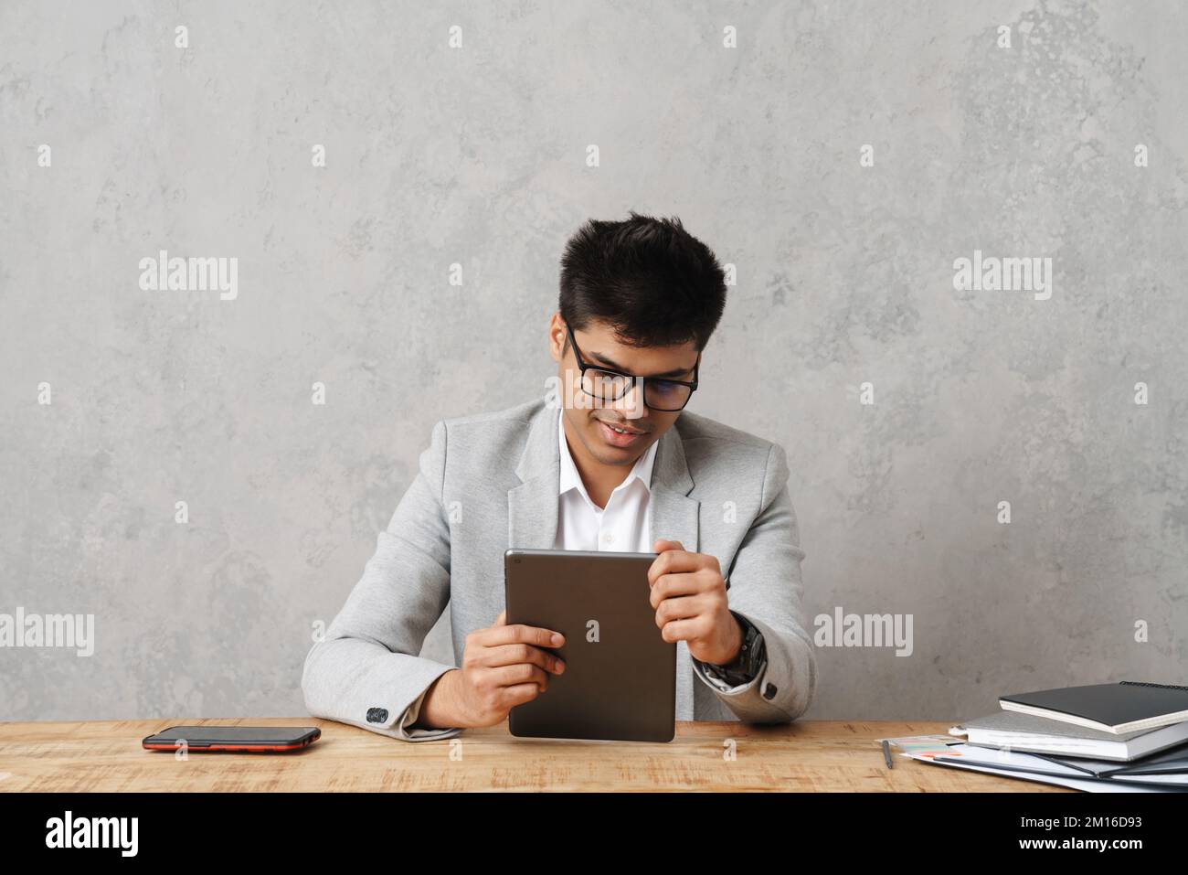 Young brunette indian businessman using tablet computer and sitting at ...
