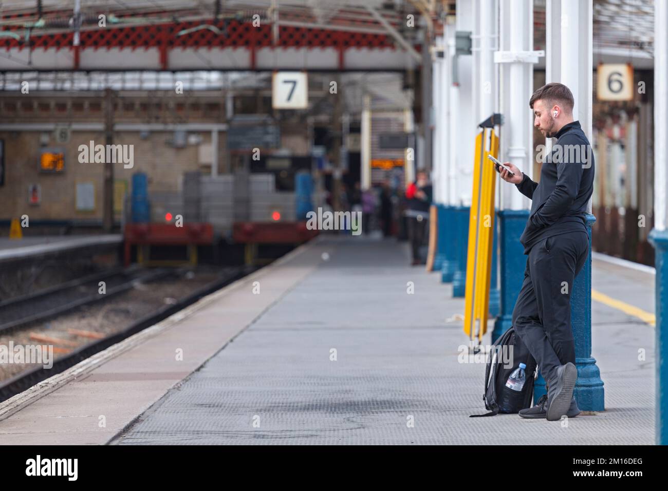 Rail passenger looking at his phone on a deserted railway station ...