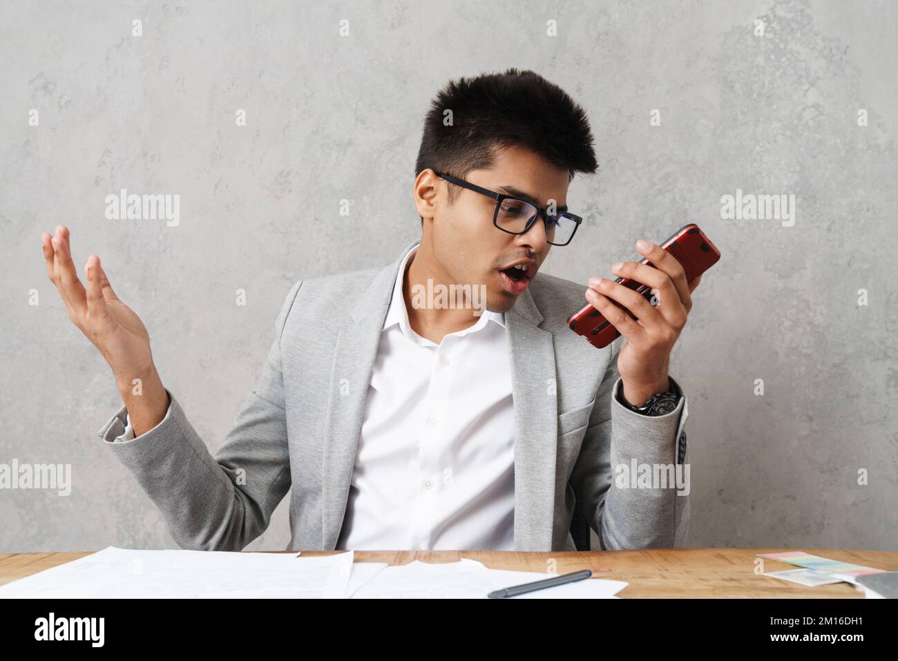 Young serious indian businessman using cellphone while working with ...