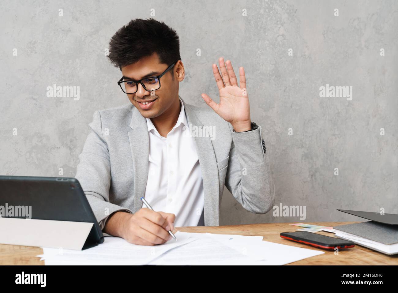Young happy indian businessman using tablet computer while working with ...