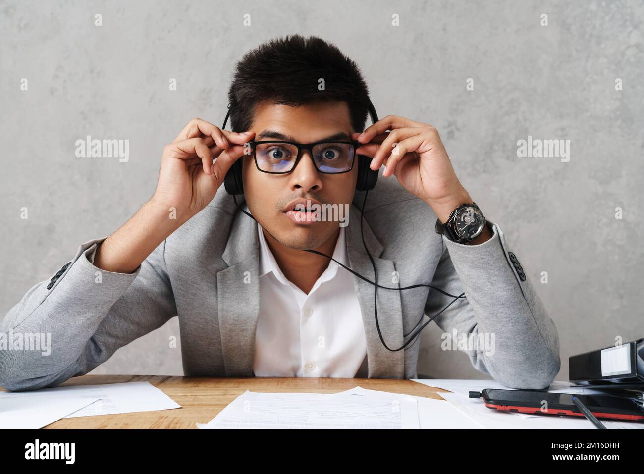 Young brunette indian businessman using cellphone and headphones while ...