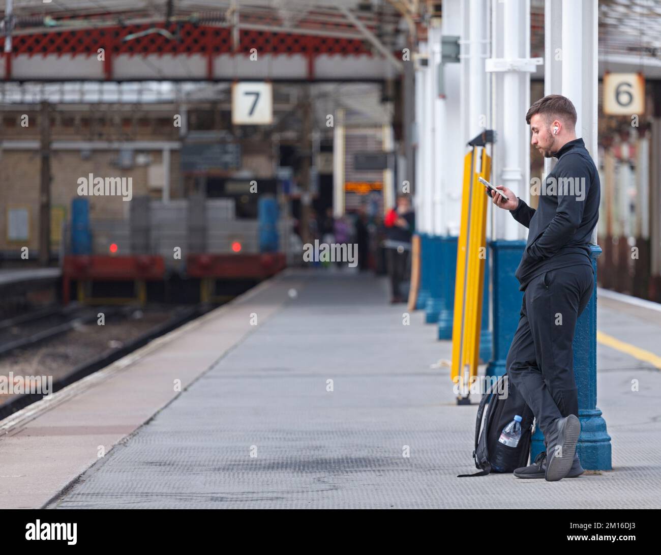 Rail passenger looking at his phone on a deserted railway station ...