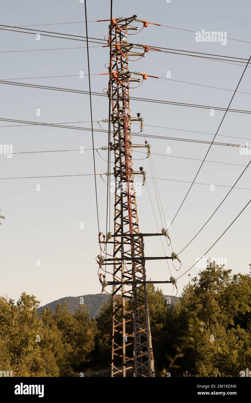 A vertical shot of an electric pole and cables on a clear sky ...