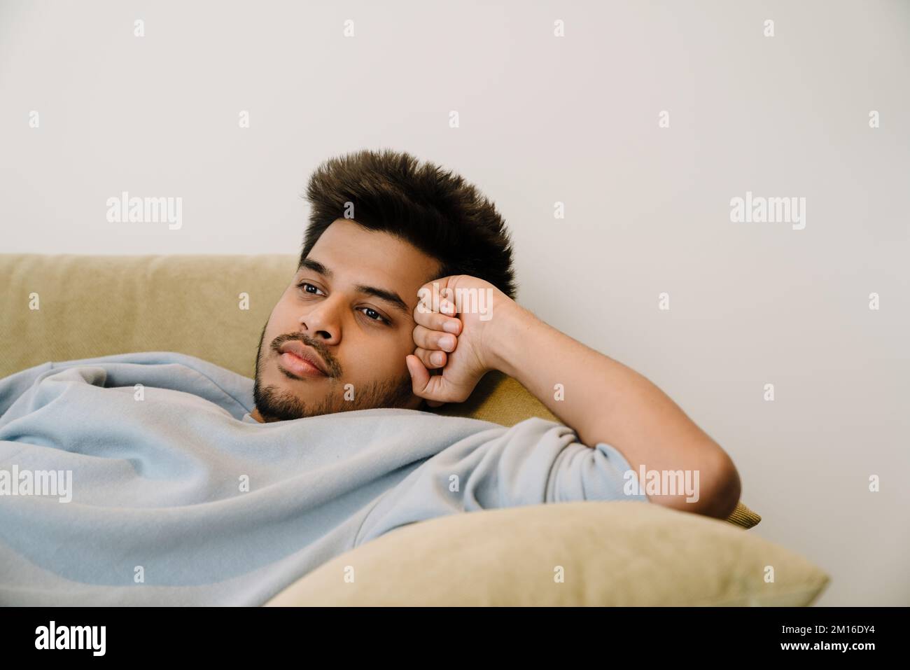 Young indian boring man liying on sofa at home Stock Photo - Alamy