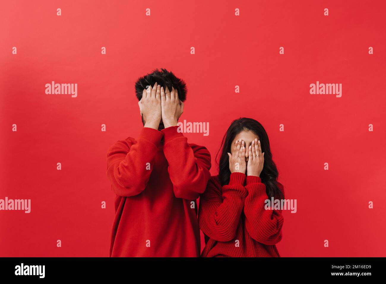 Young indian couple covering their faces with hands while posing ...