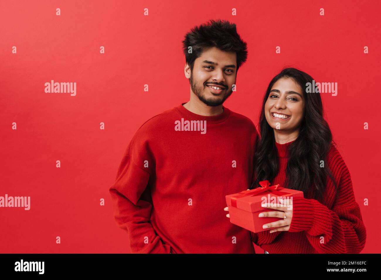 Young indian couple smiling while posing together with present box ...