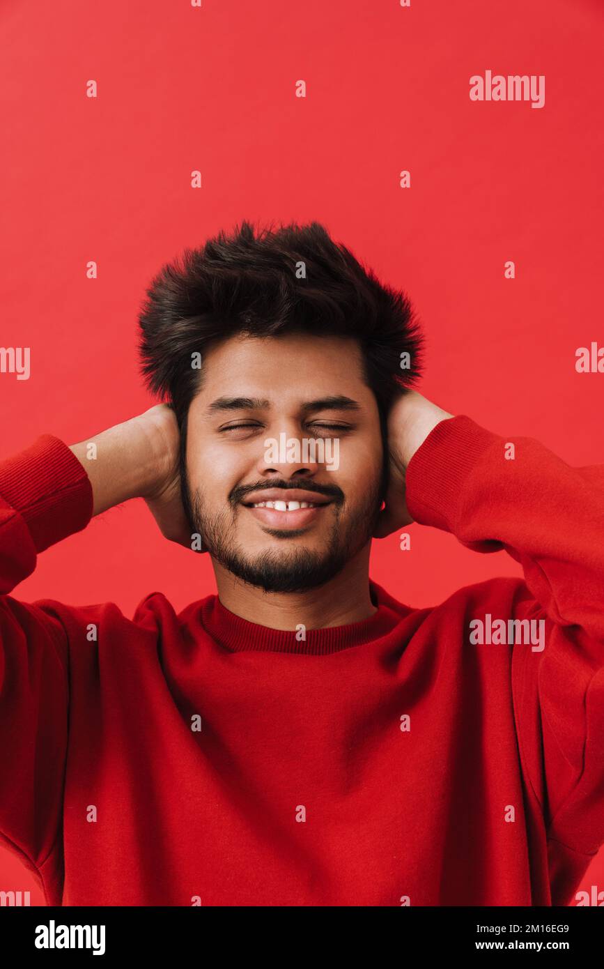 Young brunette indian man smiling and covering his ears isolated over ...