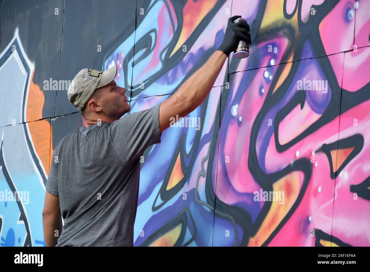 Young caucasian male graffiti artist drawing big street art painting in ...