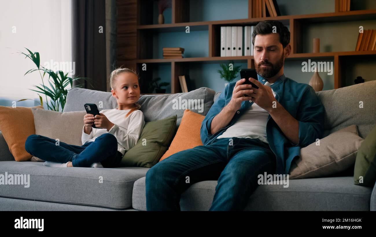 Father dad and cute child preschool girl look at mobile phone screen ...