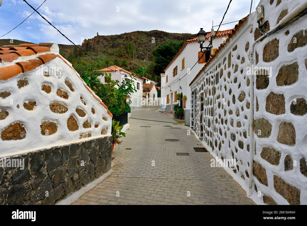 Small narrow street in the mountain village of Fataga with stone walls ...
