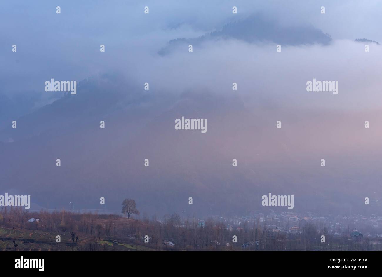 Sunrays pass through clouds covered mountain during a cold evening ...