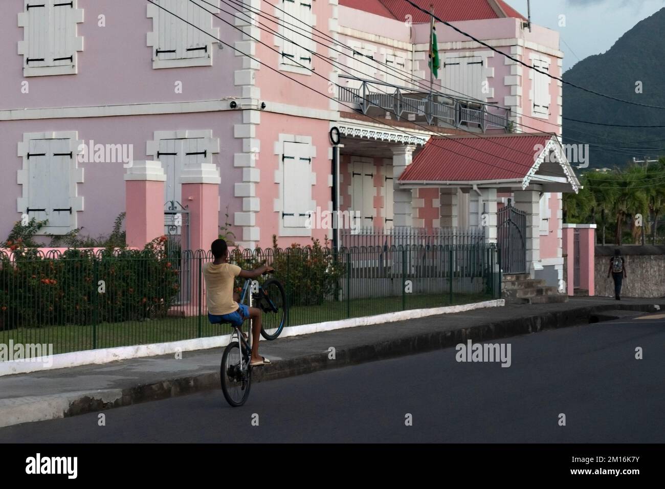 Boy riding his bike on the back wheel on the street of Roseau, Dominica ...