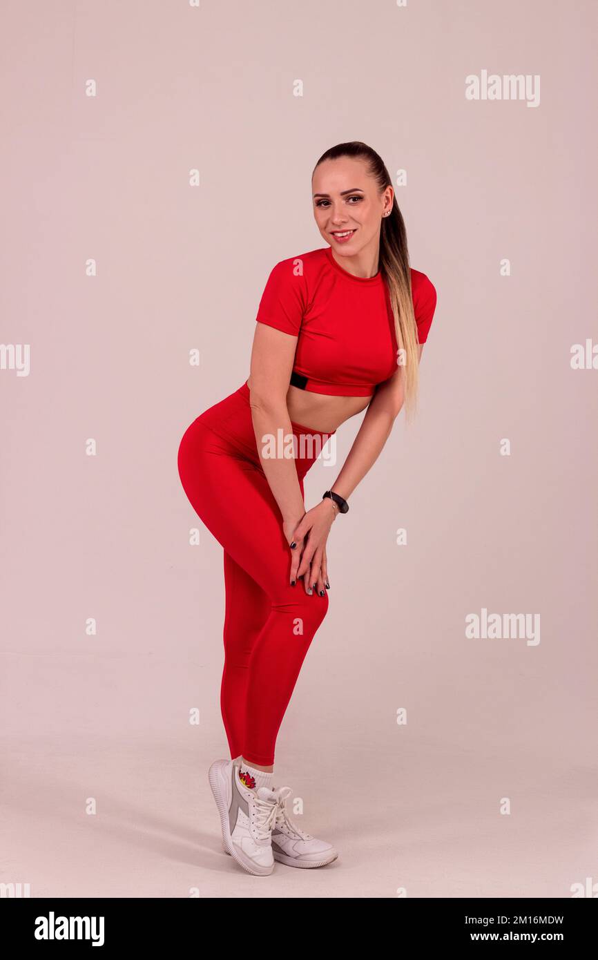 A young woman in a red tracksuit goes in for sports on a white ...