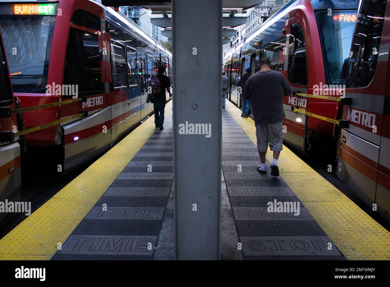 The red metro trains passing in two lanes and people walking on the ...