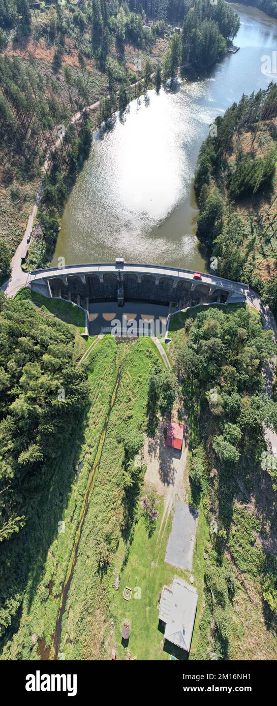 A vertical aerial view of the stone dam with an arch bridge of the ...