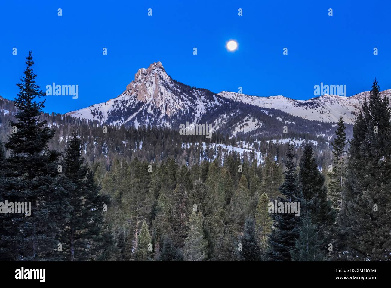 full moon setting behind ross peak in the bridger mountains in winter ...