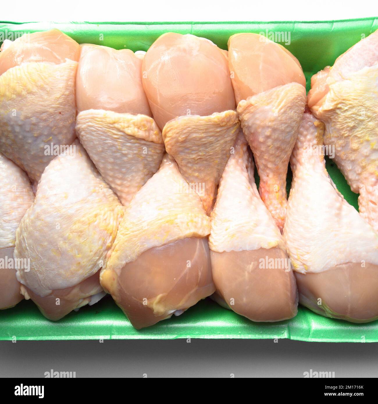 Fresh uncooked chicken meat drumsticks pieces, in green package baget ...