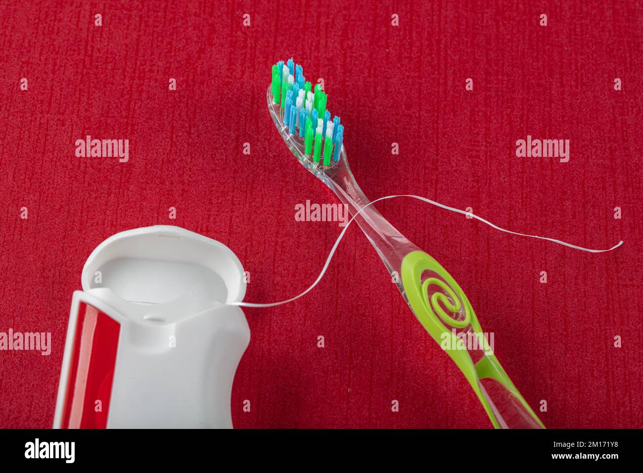 Dental floss and toothbrushes on red background. Care of teeth health ...