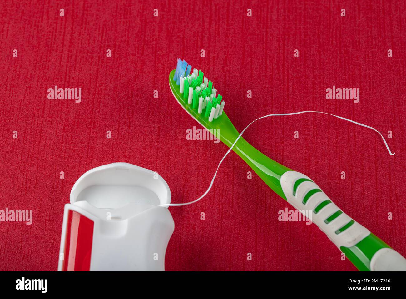 Dental floss and toothbrushes on red background. Care of teeth health ...
