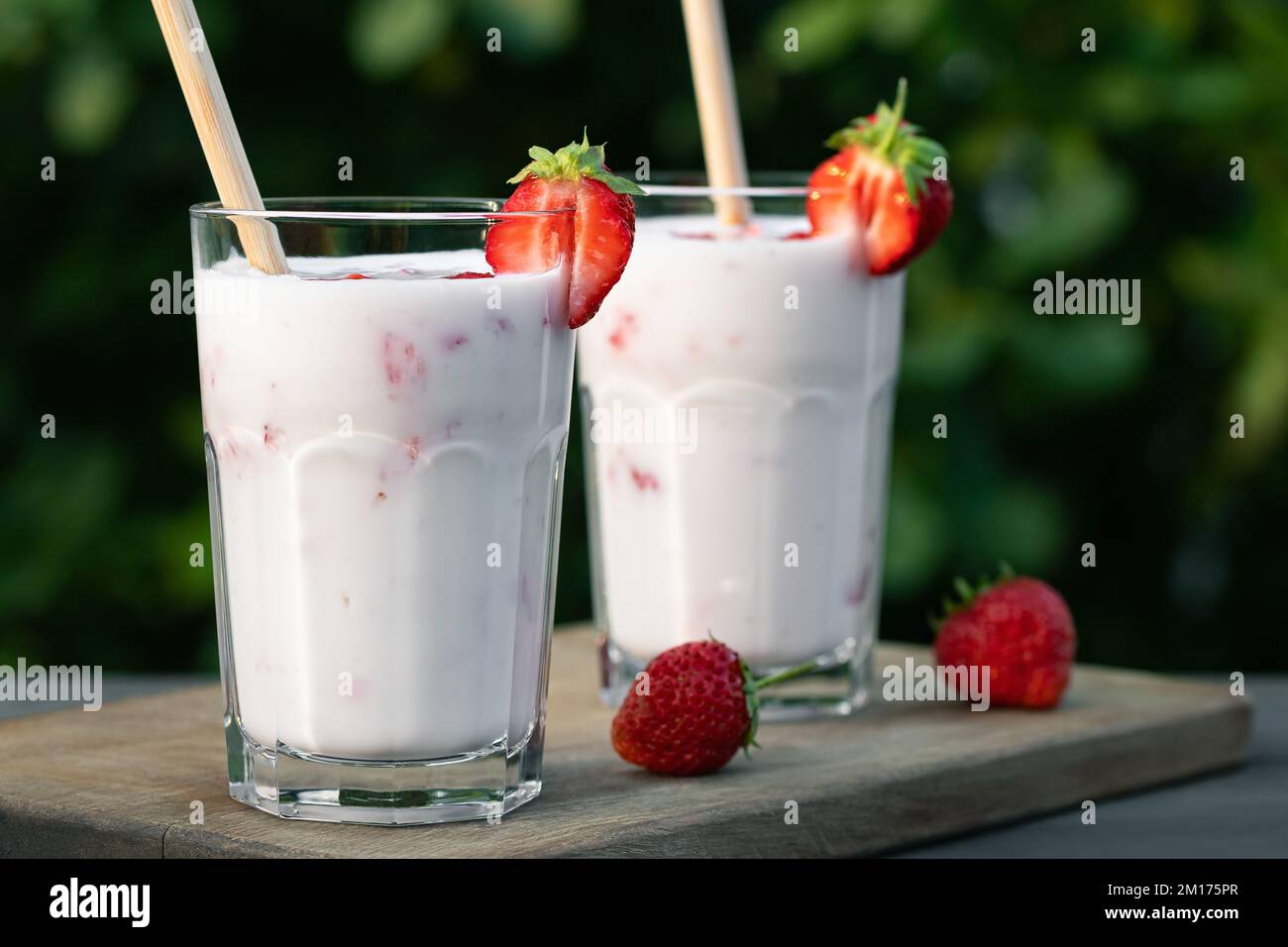 Strawberry smoothie in two glass glasses and fresh strawberries on a ...