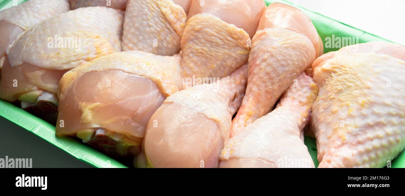 Fresh uncooked chicken meat drumsticks pieces, in green package baget ...