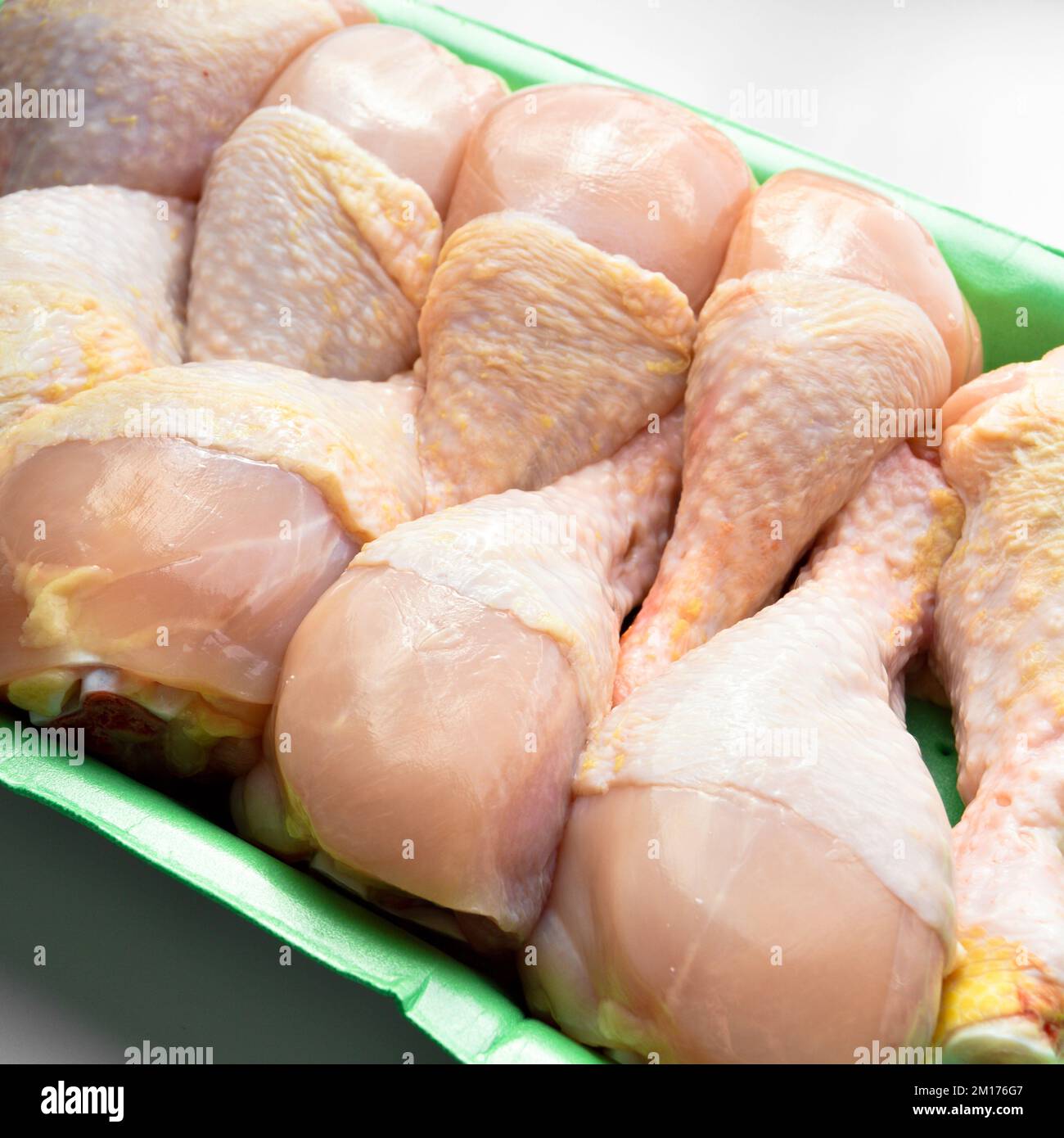 Fresh uncooked chicken meat drumsticks pieces, in green package baget ...