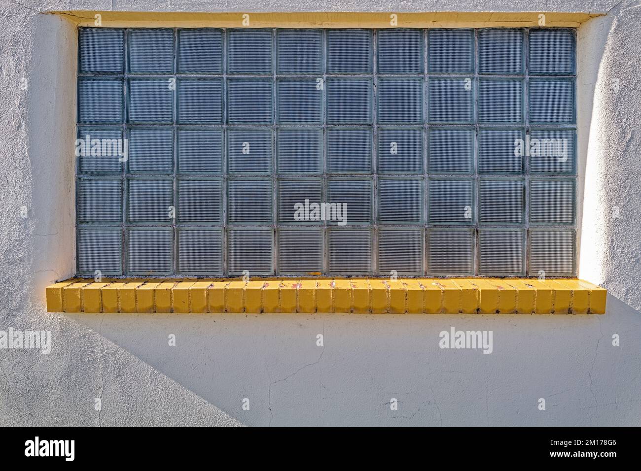 A glass block window installed on the plaster wall of a building with a ...
