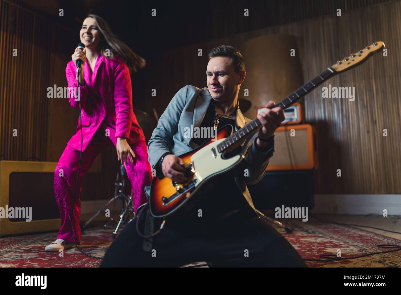 musical band, young guitarist on a floor and singer woman in pink ...