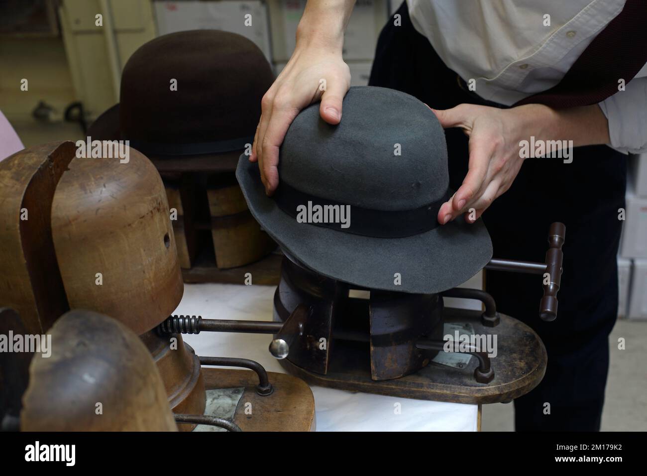 Lock & Co Hatters staff member uses steam to reshape a hat, London ...