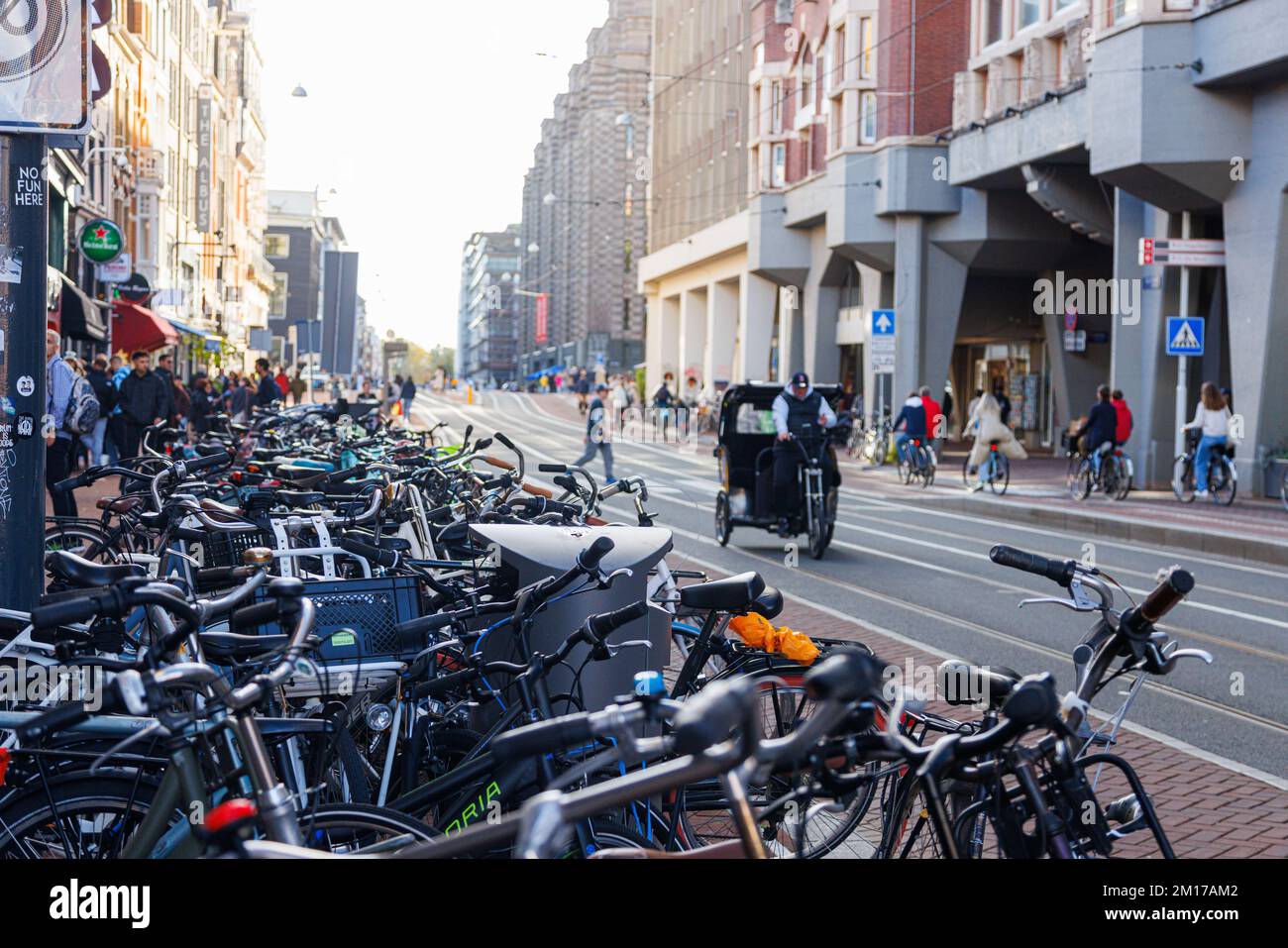 Ordinary Amsterdam street with parked bicycles and cyclists ...