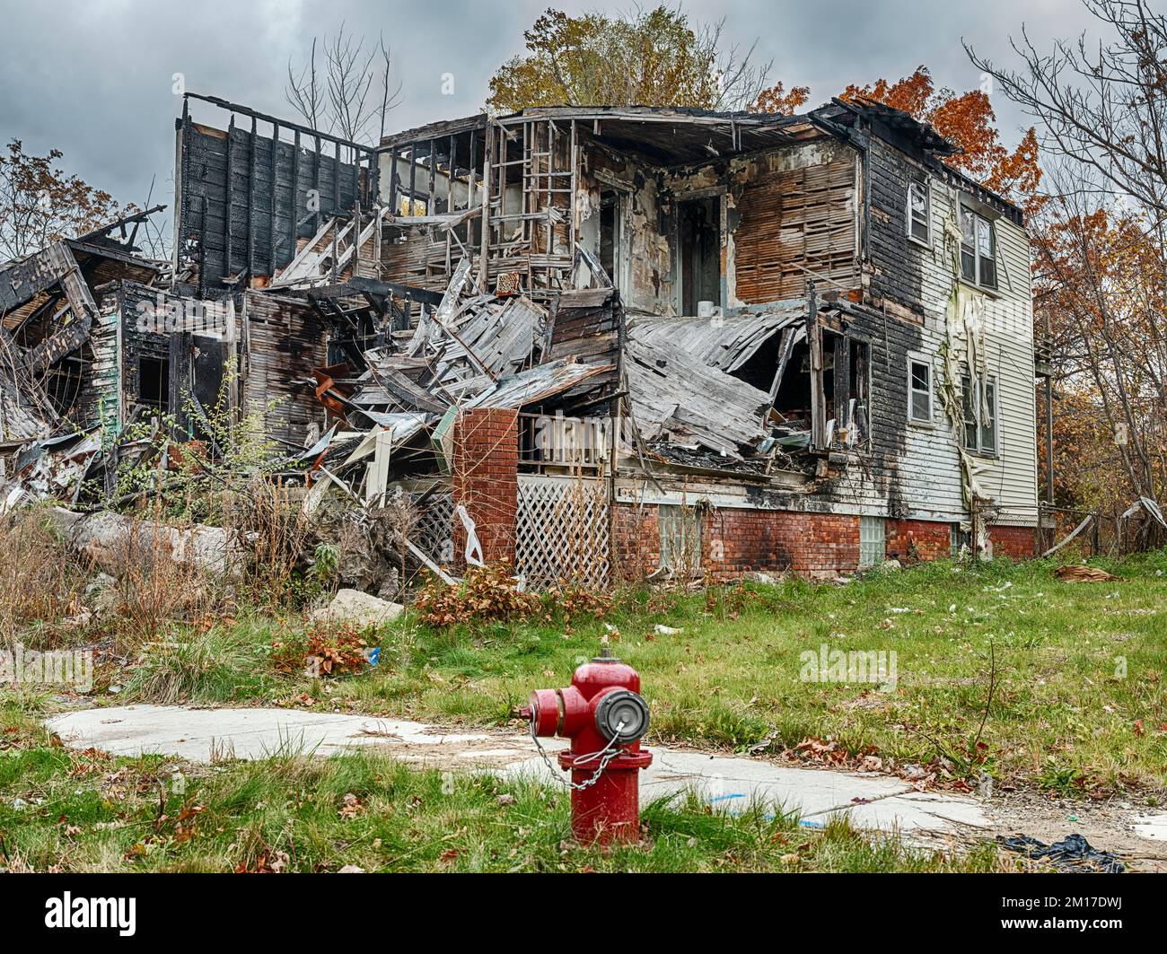 A red fire hydrant stands in front of a burned and semi-demolished ...