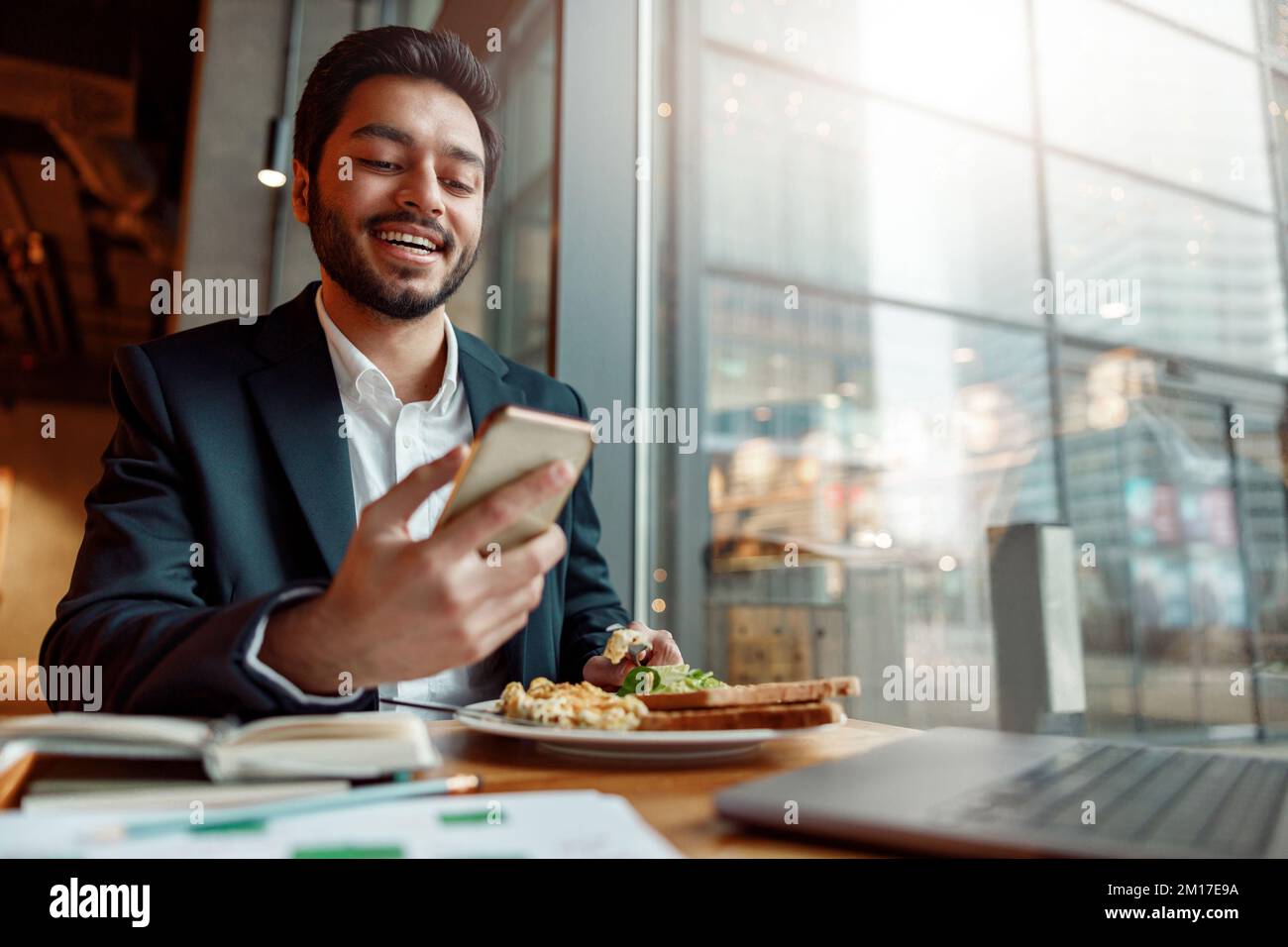Smiling Indian businessman wearing suit is using phone during lunch ...