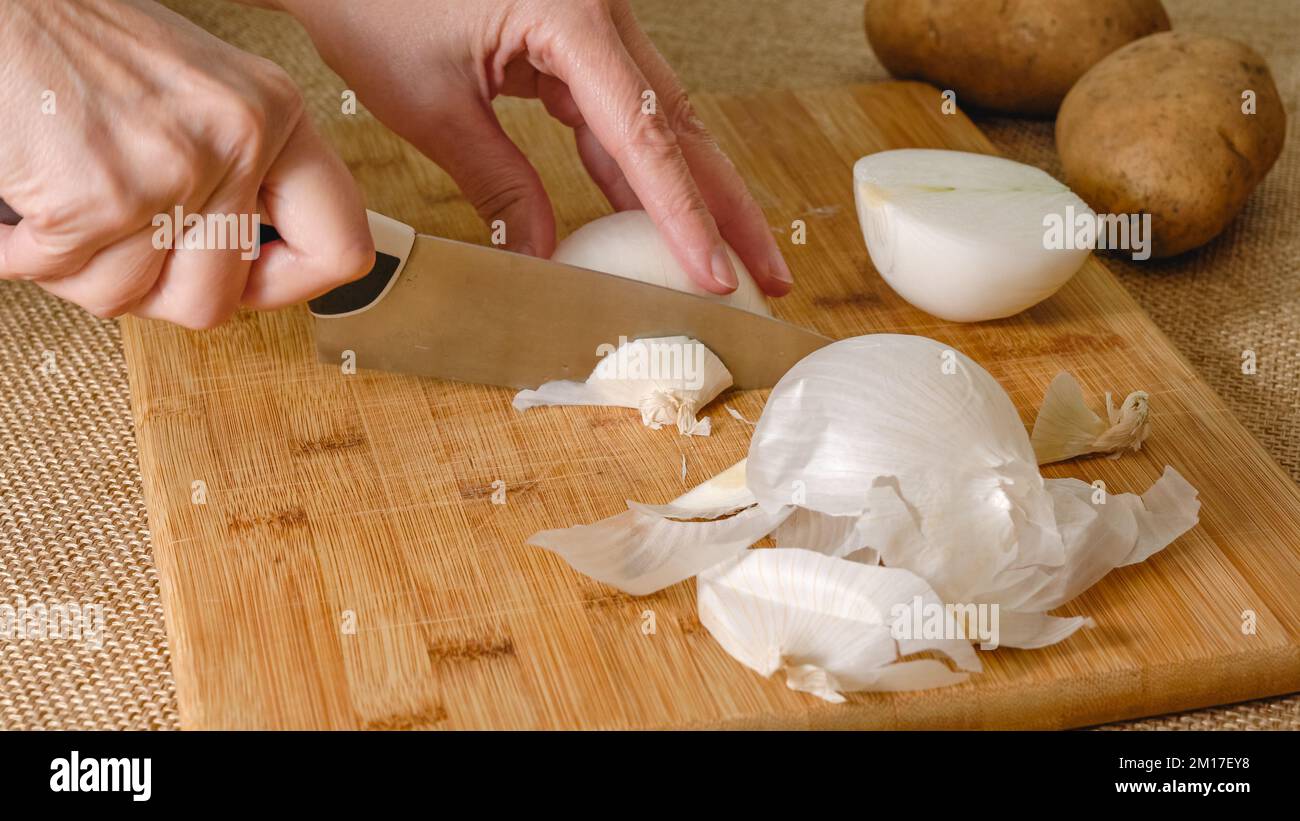 Peeling and cutting white onion on a cutting board. Vegetable soup ...