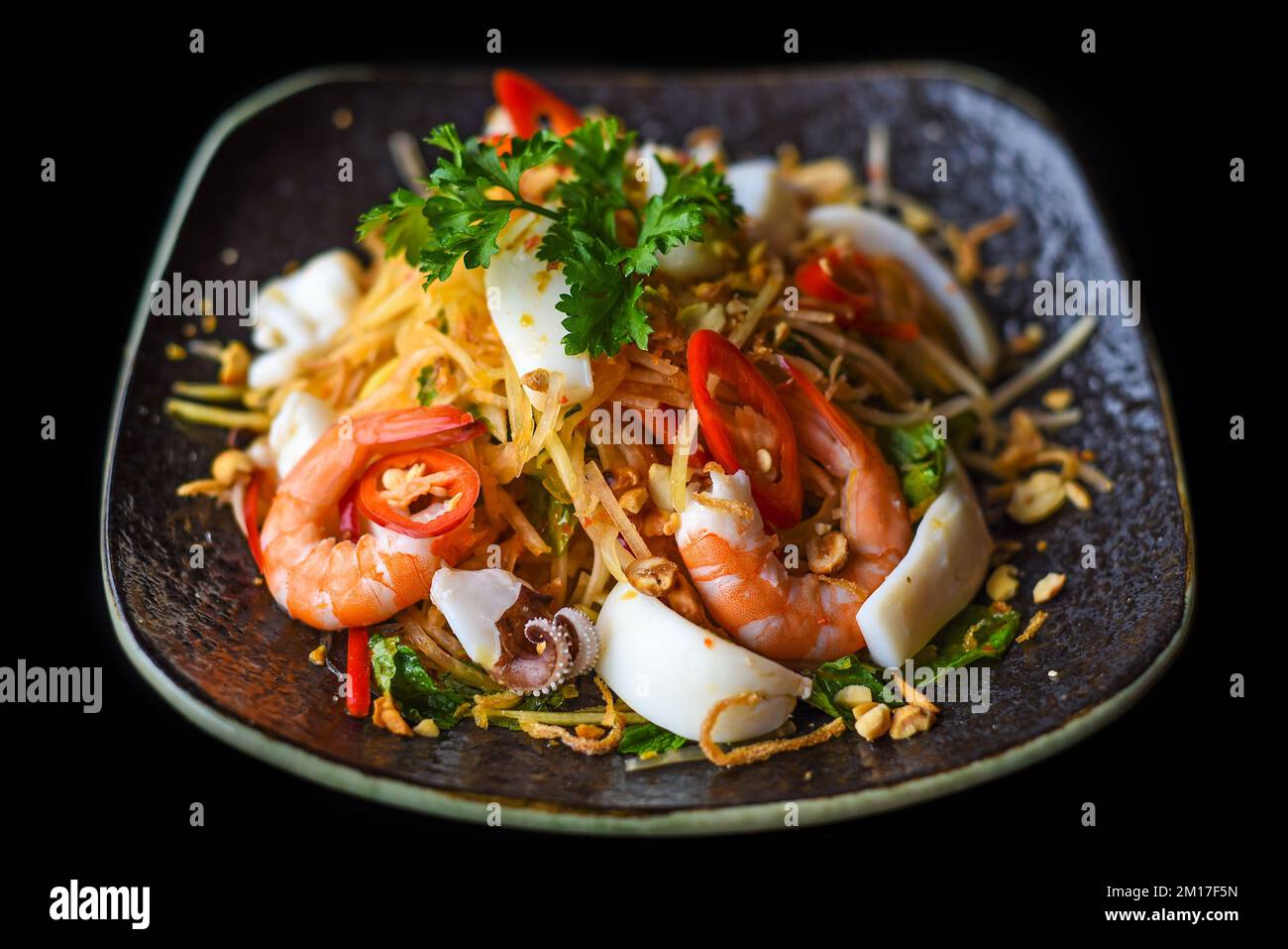 Salad made of shrimps and squid isolated on black background side view ...