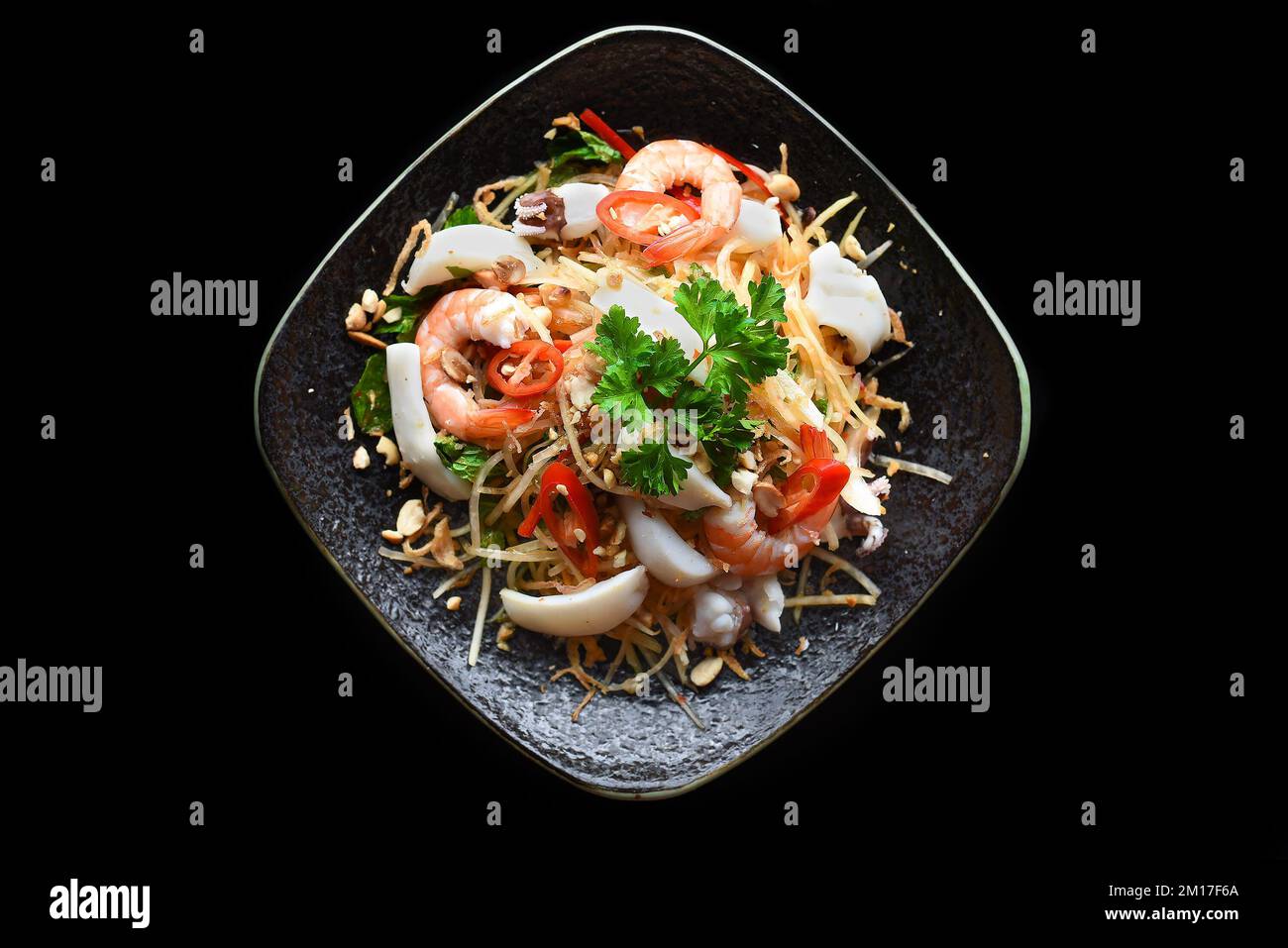 Salad made of shrimps and squid isolated on black background side view ...