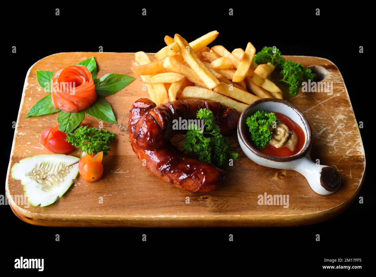 Fried sausages with french fries and spicy sauce on wooden board ...