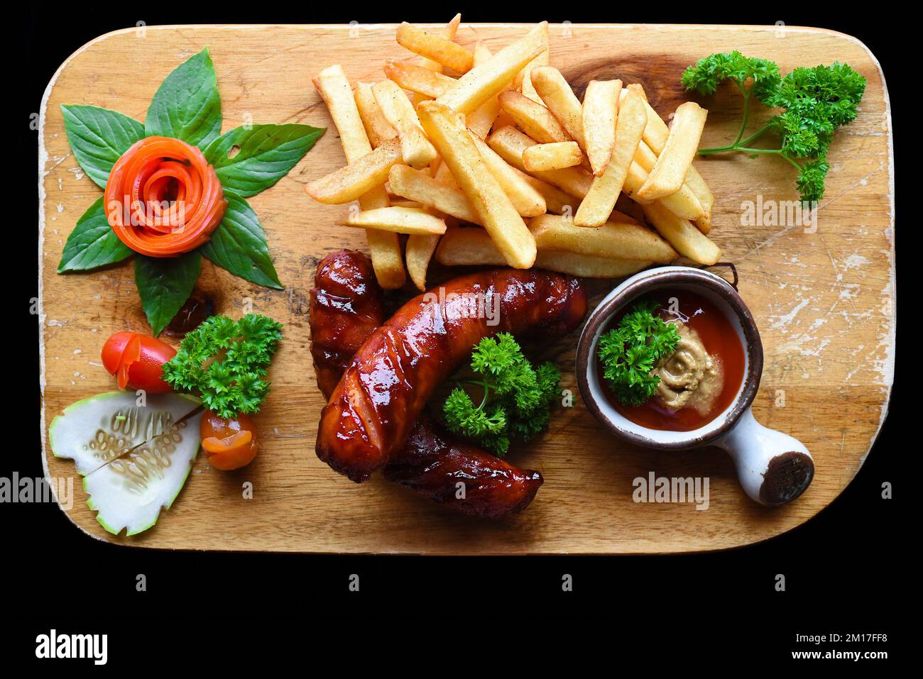 Fried sausages with french fries and spicy sauce on wooden board ...