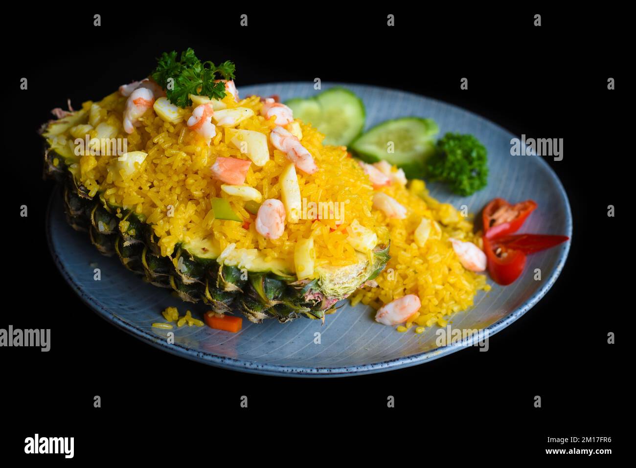 Fried rice with seafood in a pineapple with vegetables on blue plate ...