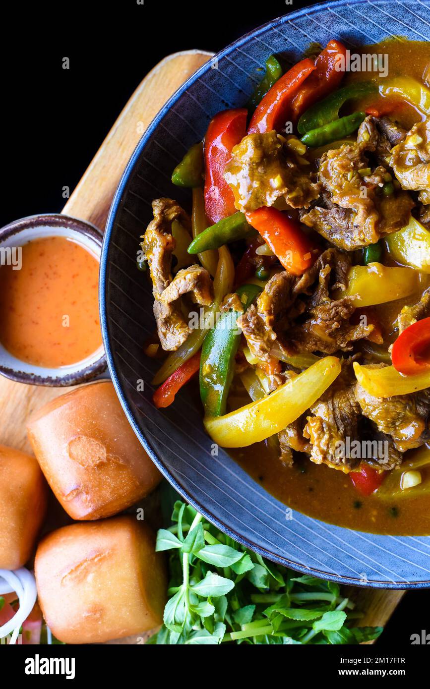 Beef stew with vegetables and banh mi bread on wooden chop board ...