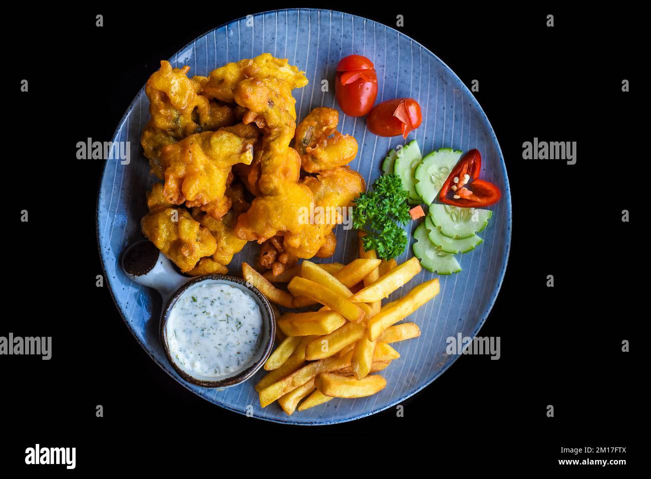 Fried frog in batter with french fries on blue plate isolated on black ...
