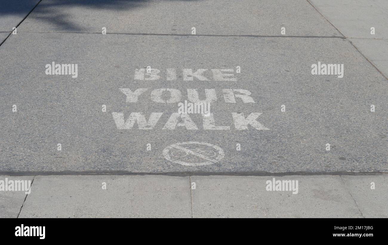 Walk Your Bike sign written on the asphalt on the boardwalk in Venice ...