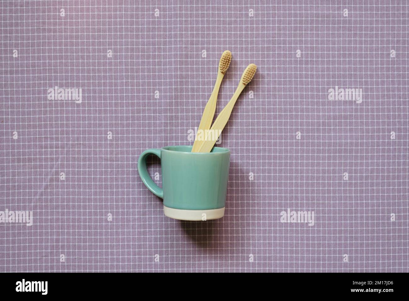 Bamboo wood toothbrush in mint color cup on purple check pattern fabric ...