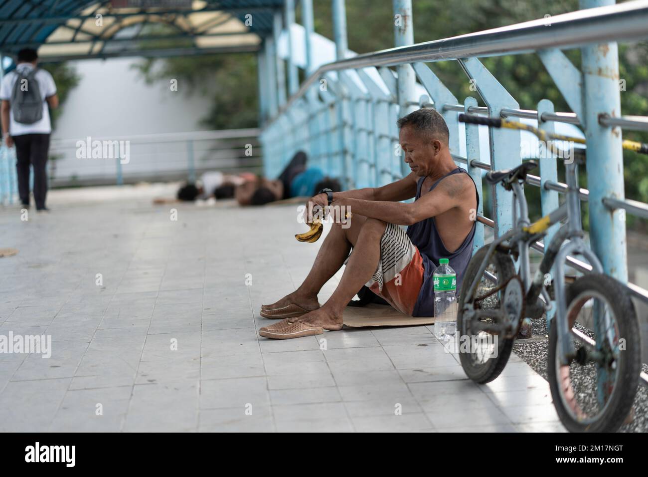 A homeless man on a flyover sitting on a piece of cardboard, Cebu City ...
