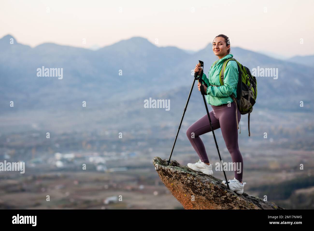 Hiker girl resting on a rock pedestal after long day trekking. Woman ...