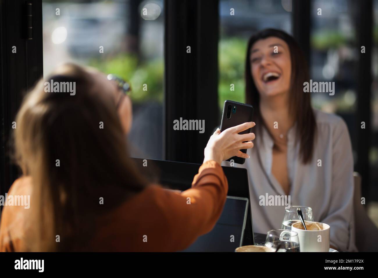 Two young business women in a cafe having one on one meeting. Friends ...