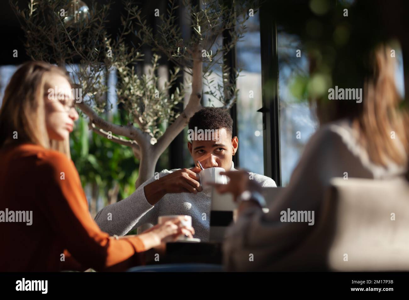 Three friends in a restaurant talking smiling and drinking tea ...