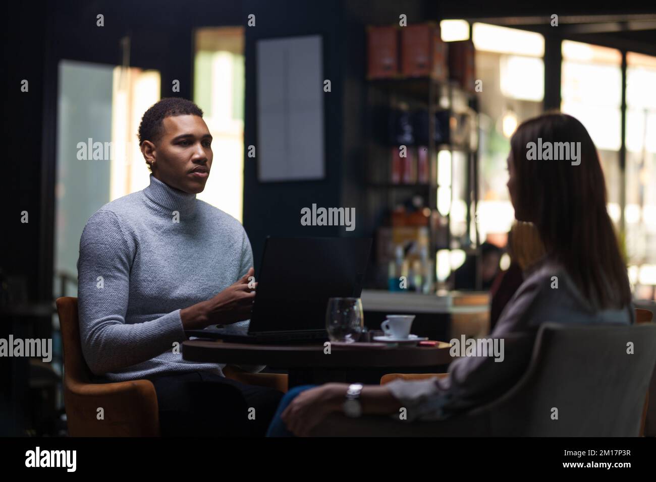 Friends at a cafe after work. Business colleagues working on laptop and ...