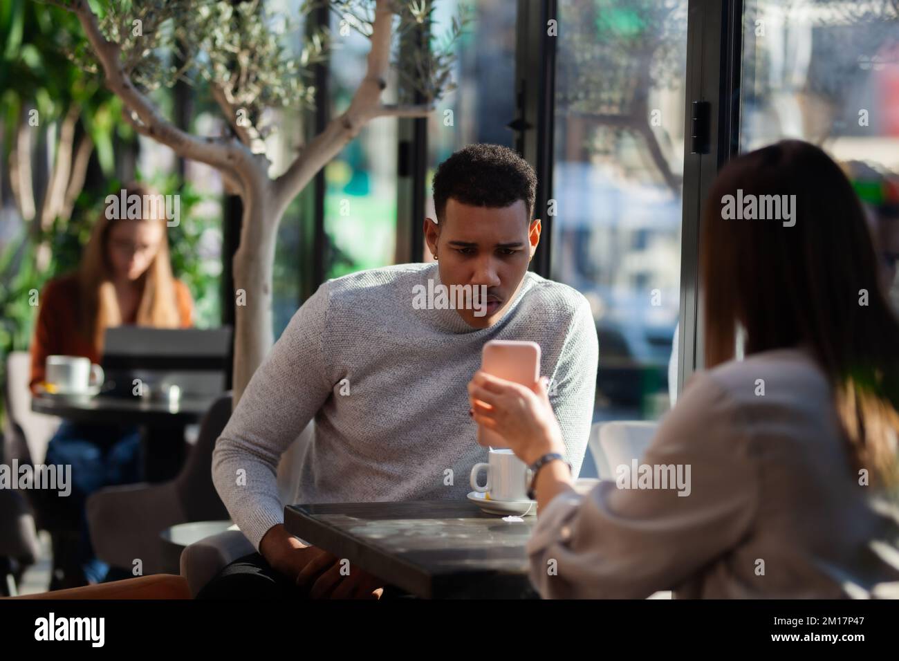 Two friends in a restaurant talking smiling and drinking tea ...