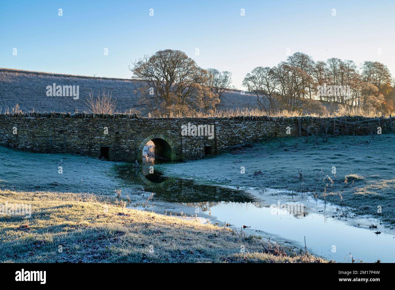 River Leach and stone bridge on the a frosty morning. Hatherop estate ...